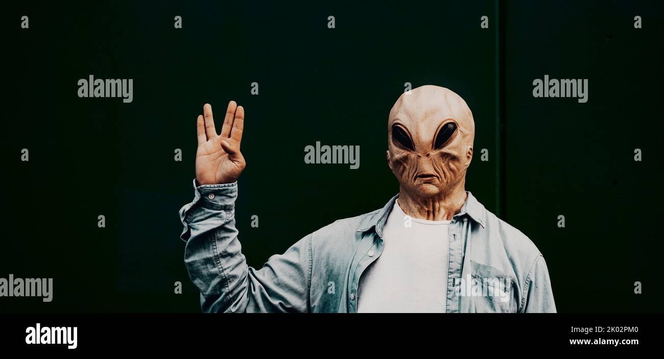 Alien mask people against a black background doing hallo gesture Stock ...