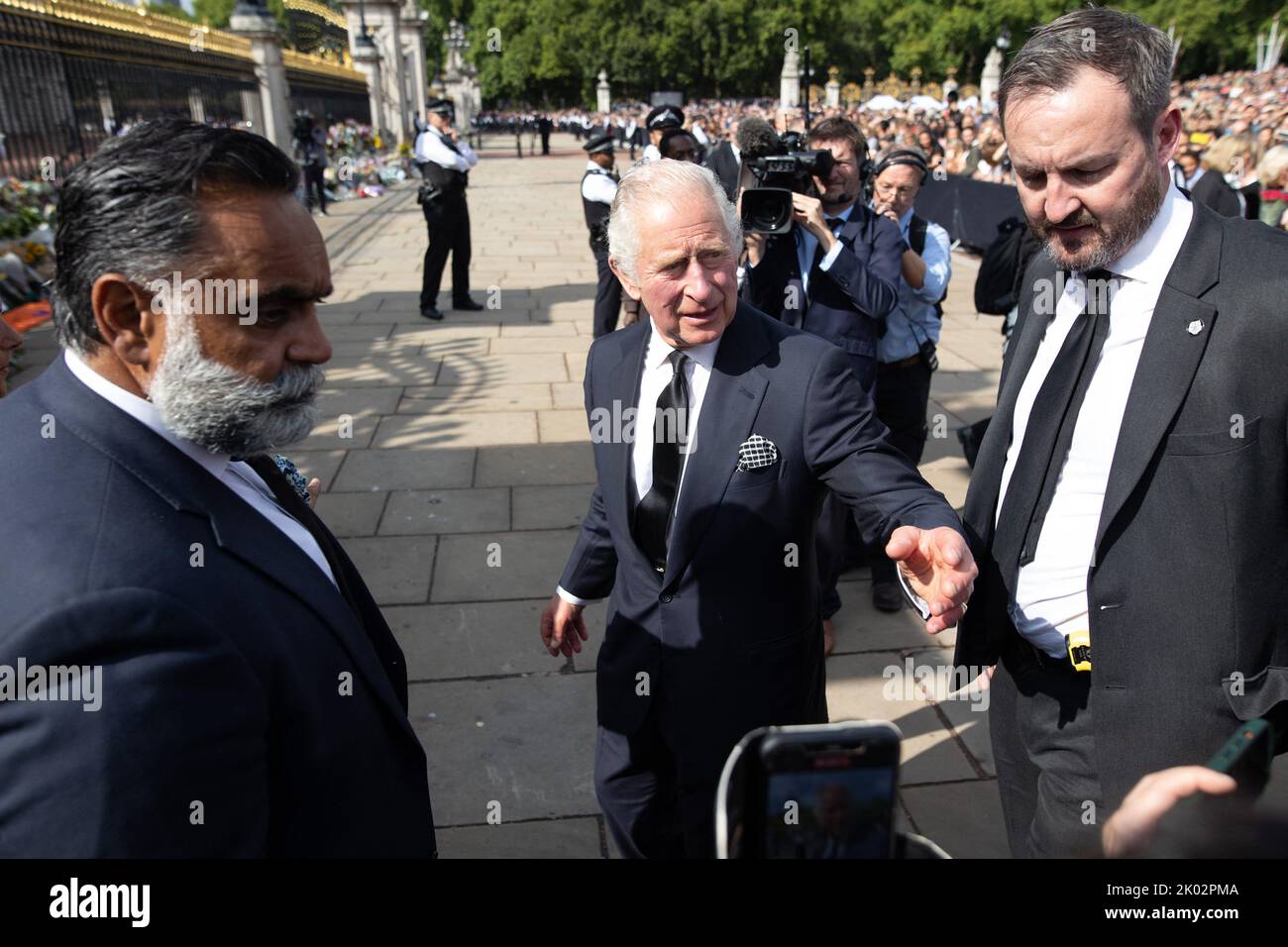 King Charles is cheered by the crowd as they walk into Buckingham Palace, following the passing ...