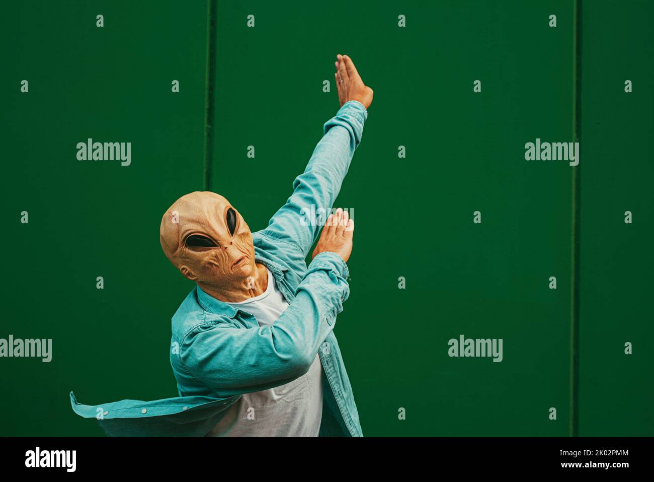 Alien doing dab posture and gesture against a green wall background ...