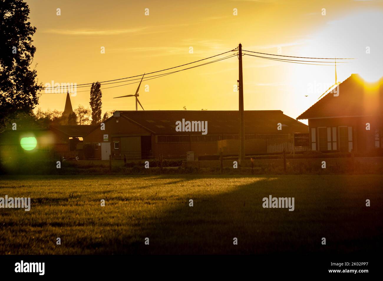 A sunset at a farm with the sun setting behind houses Stock Photo - Alamy