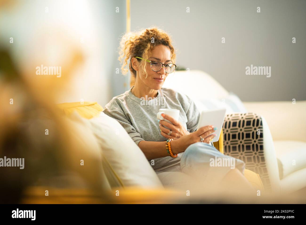 Relaxed young adult caucasian woman read a book on modern device reader ...
