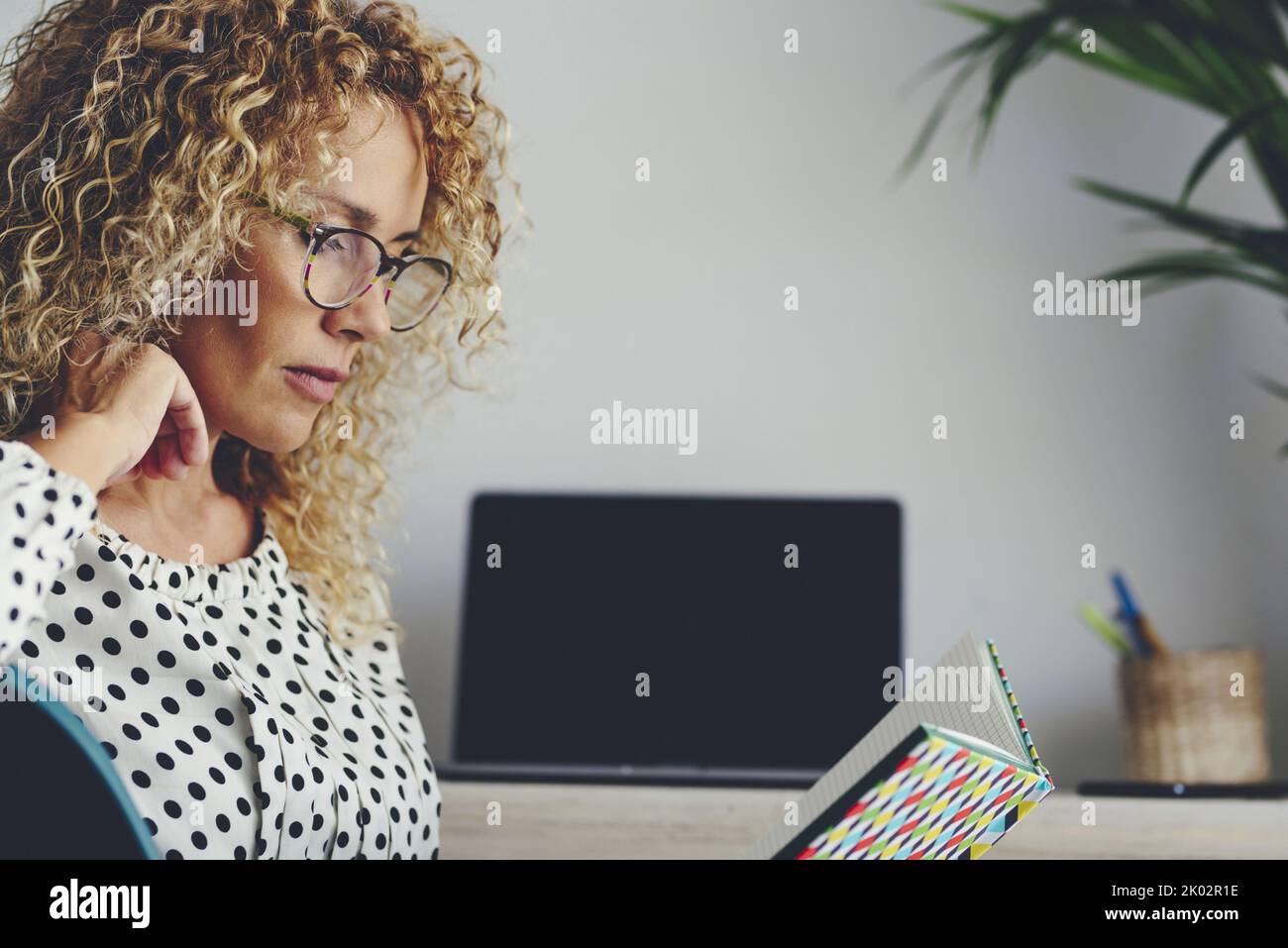 Side portrait of cute adult lady reading a notebook wearing eyeglasses ...