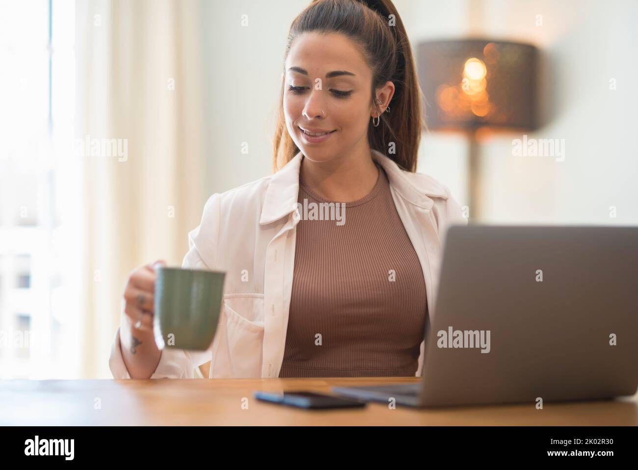 Portrait of confident young woman using computer at home. Serene female ...