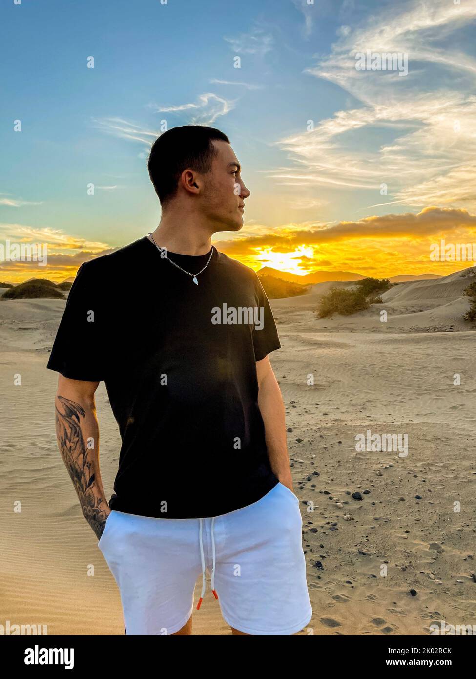Handsome young male model standing for a portrait with desert dunes and ...
