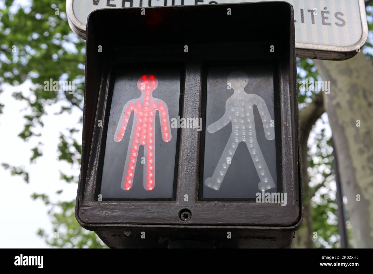 A closeup of pedestrian lights with the red light on in the street ...