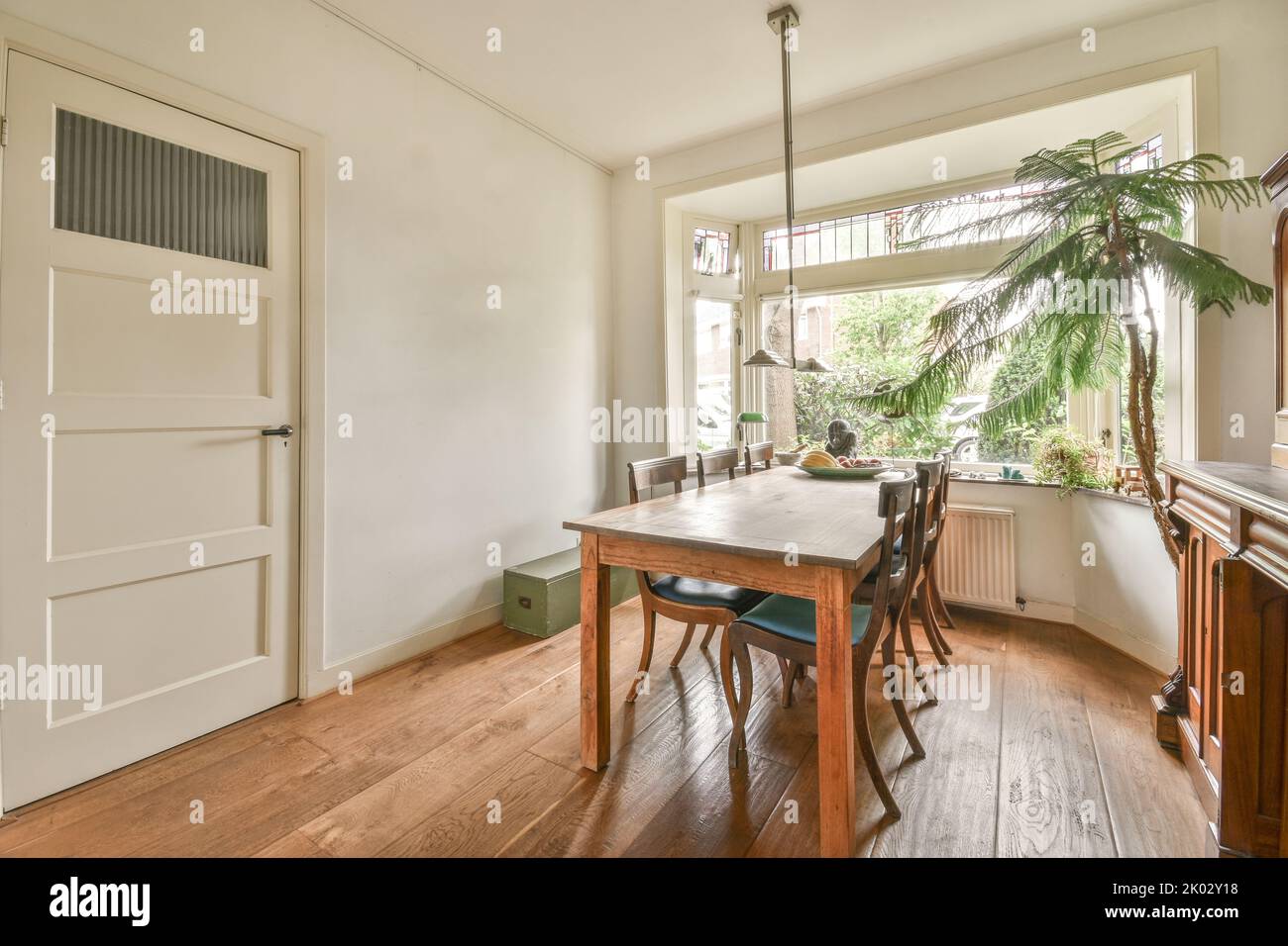 Simple table with chairs located under elegant chandelier near doors in ...