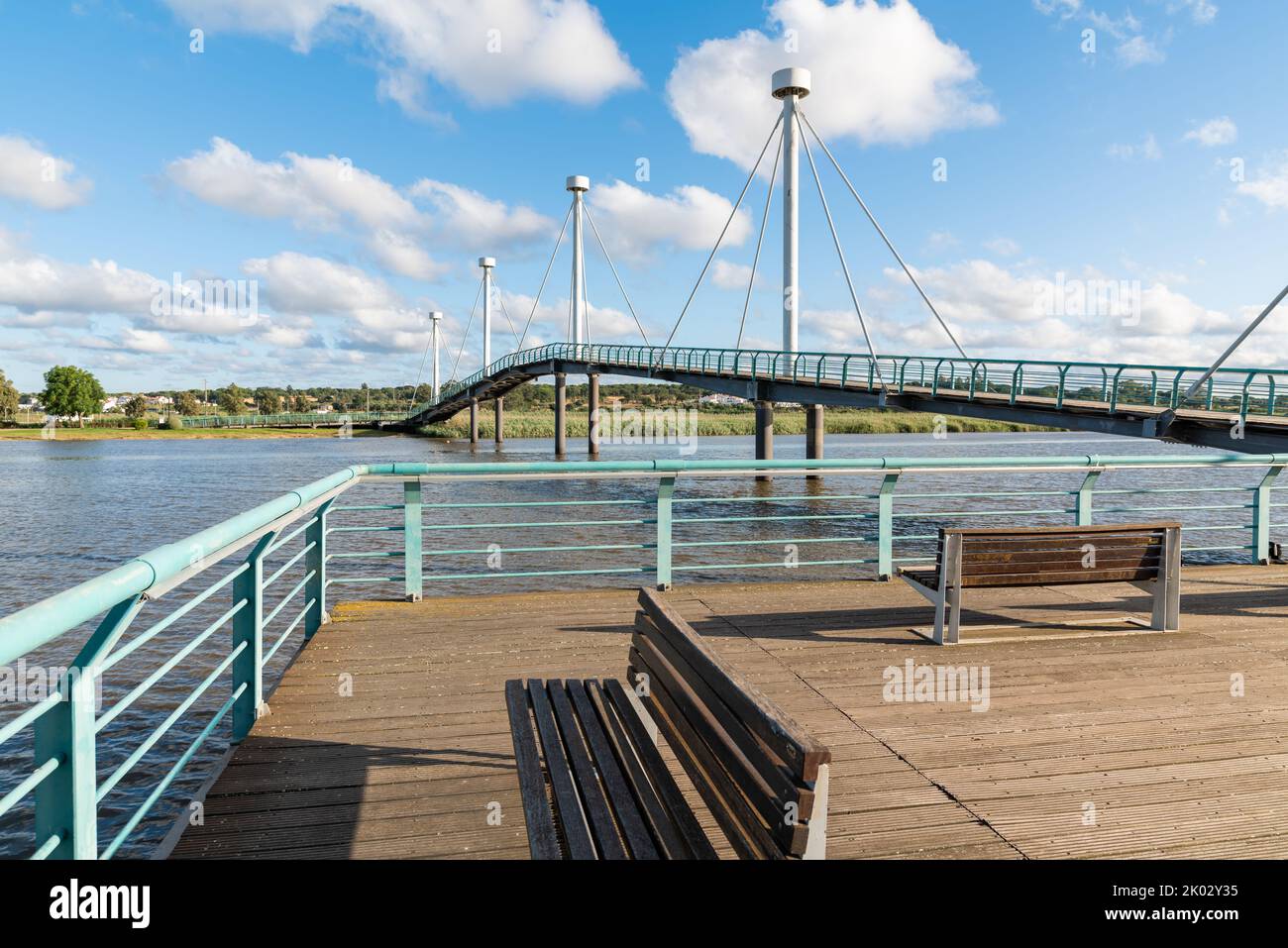 Two benches on a wooden pier connected to a bridge over a river Stock ...