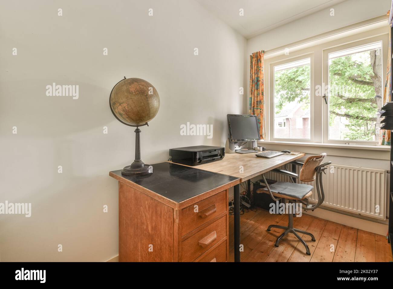 Comfortable chair placed near desk with computer monitors and printer ...