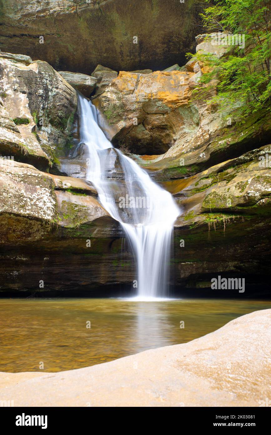 A vertical shot of a scenic waterfall coming out from a rocky hill in ...
