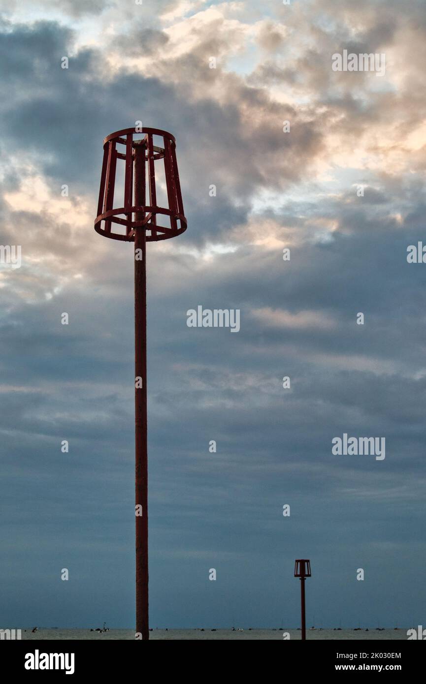 A vertical shot of a red stand for fire with a sunset cloudscape in the ...