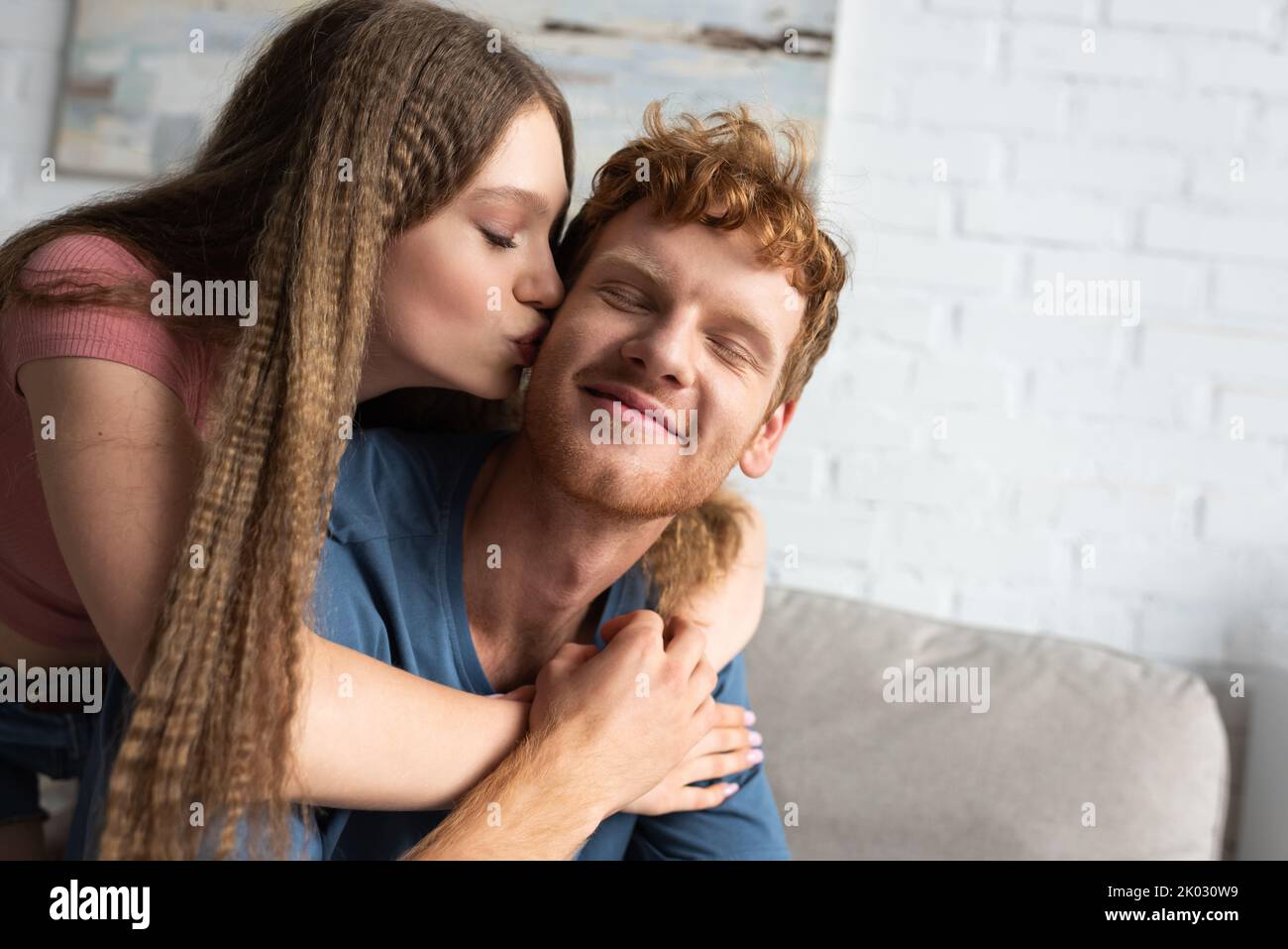 pretty teen girl hugging and kissing cheek of redhead boyfriend in ...