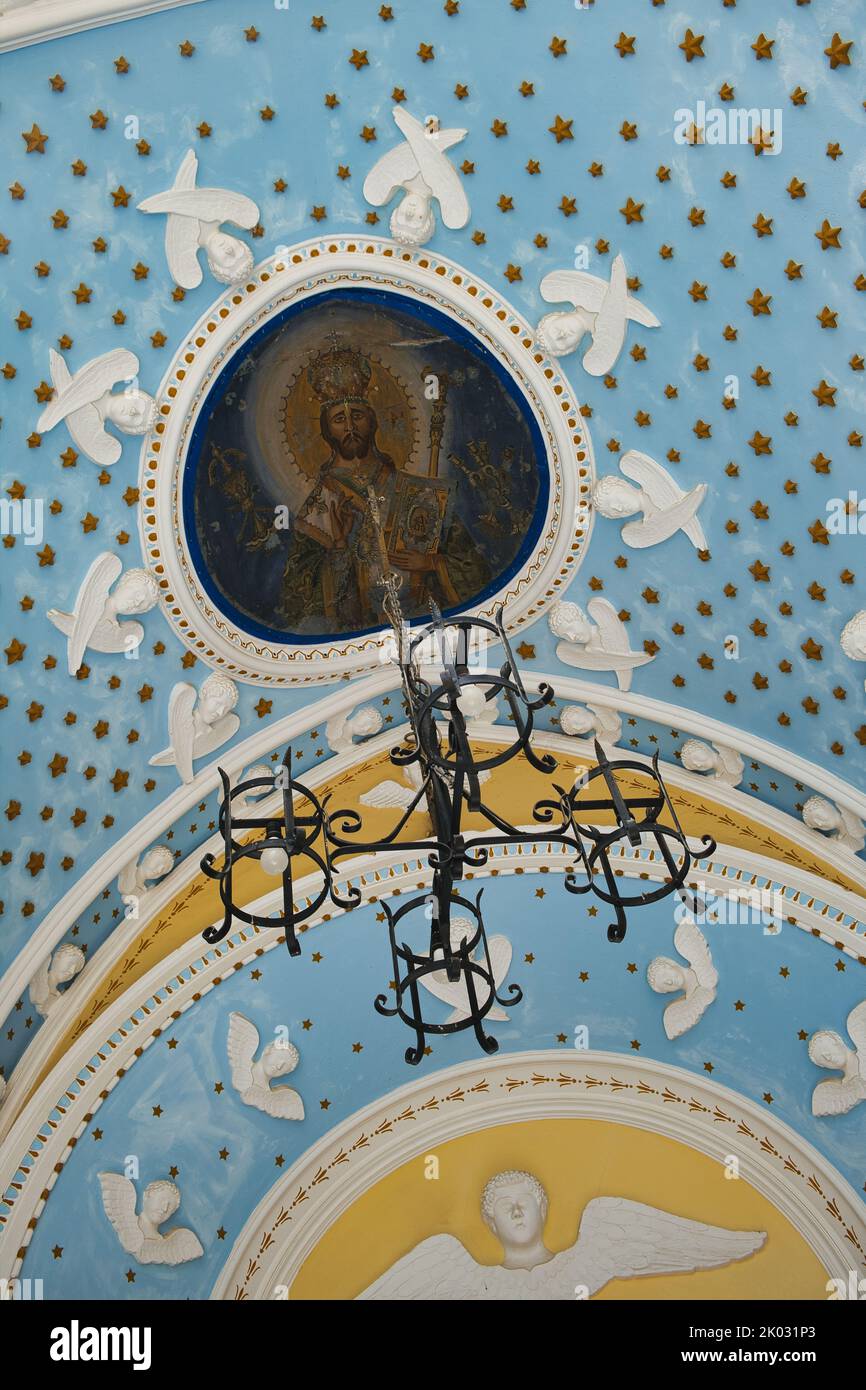 A vertical low angle shot of an old iron chandelier on a painted ...