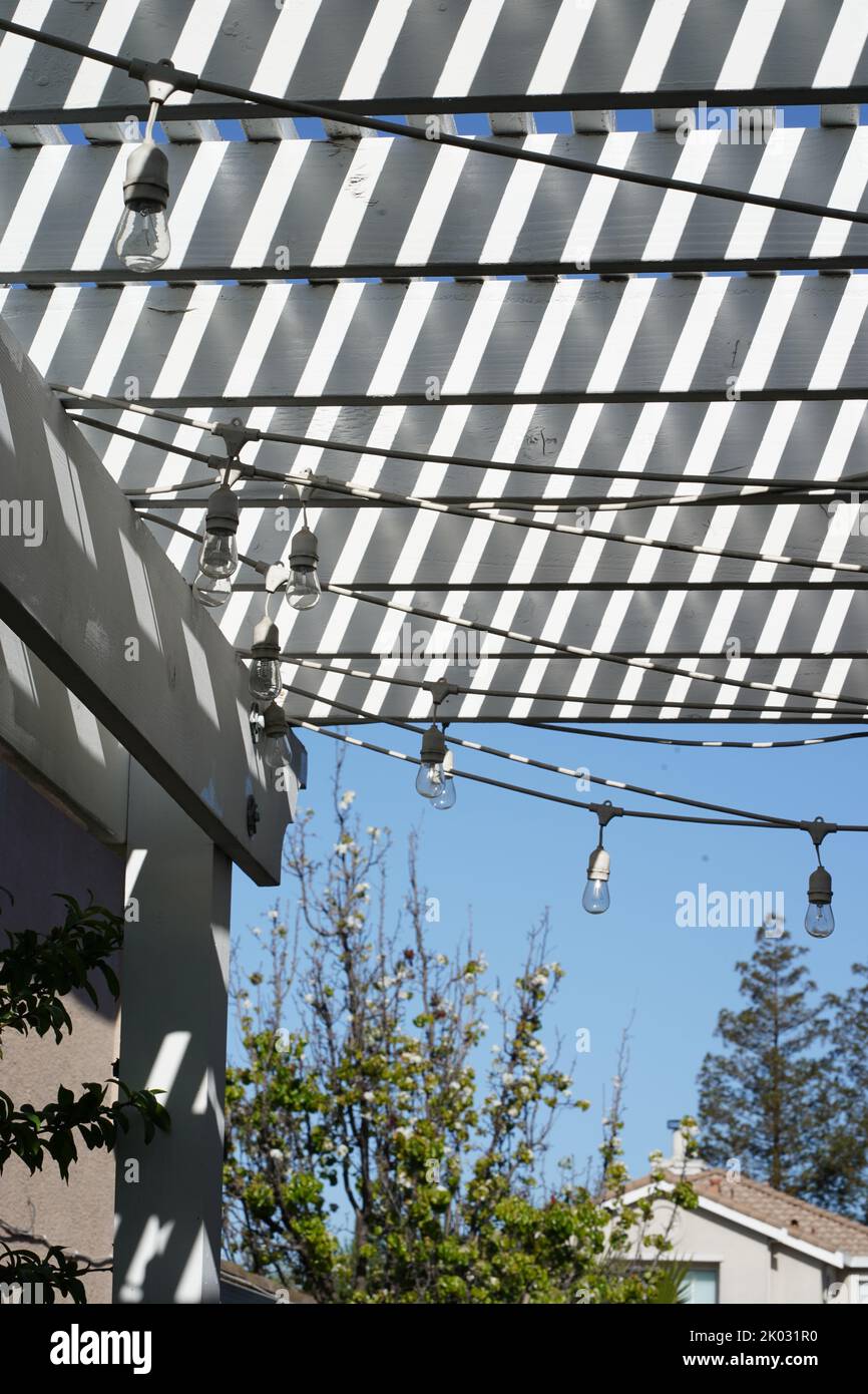 A vertical closeup shot of a white wooden striped canopy over a yard on ...