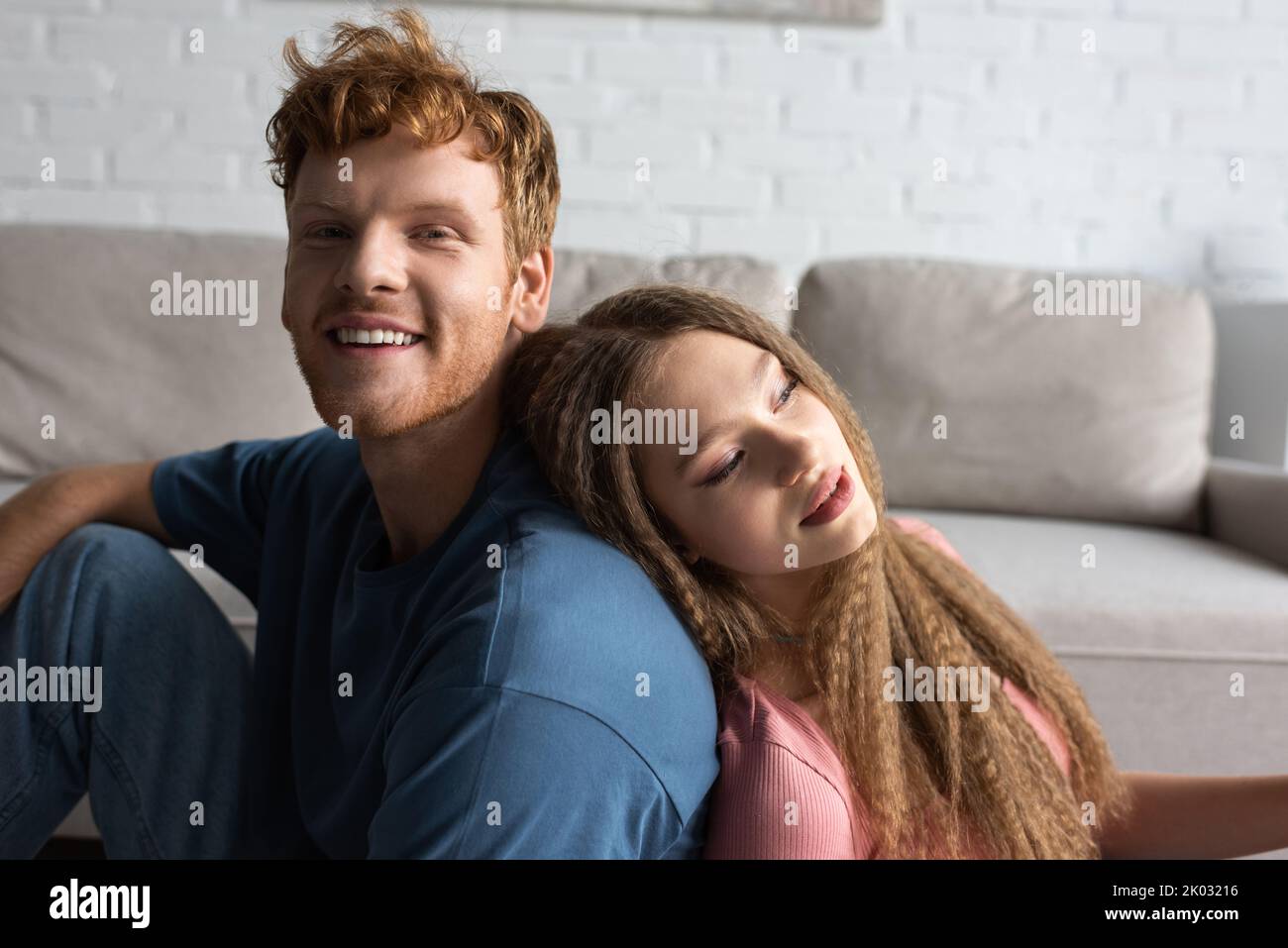 pretty teenage girl leaning on back of positive boyfriend with red hair ...