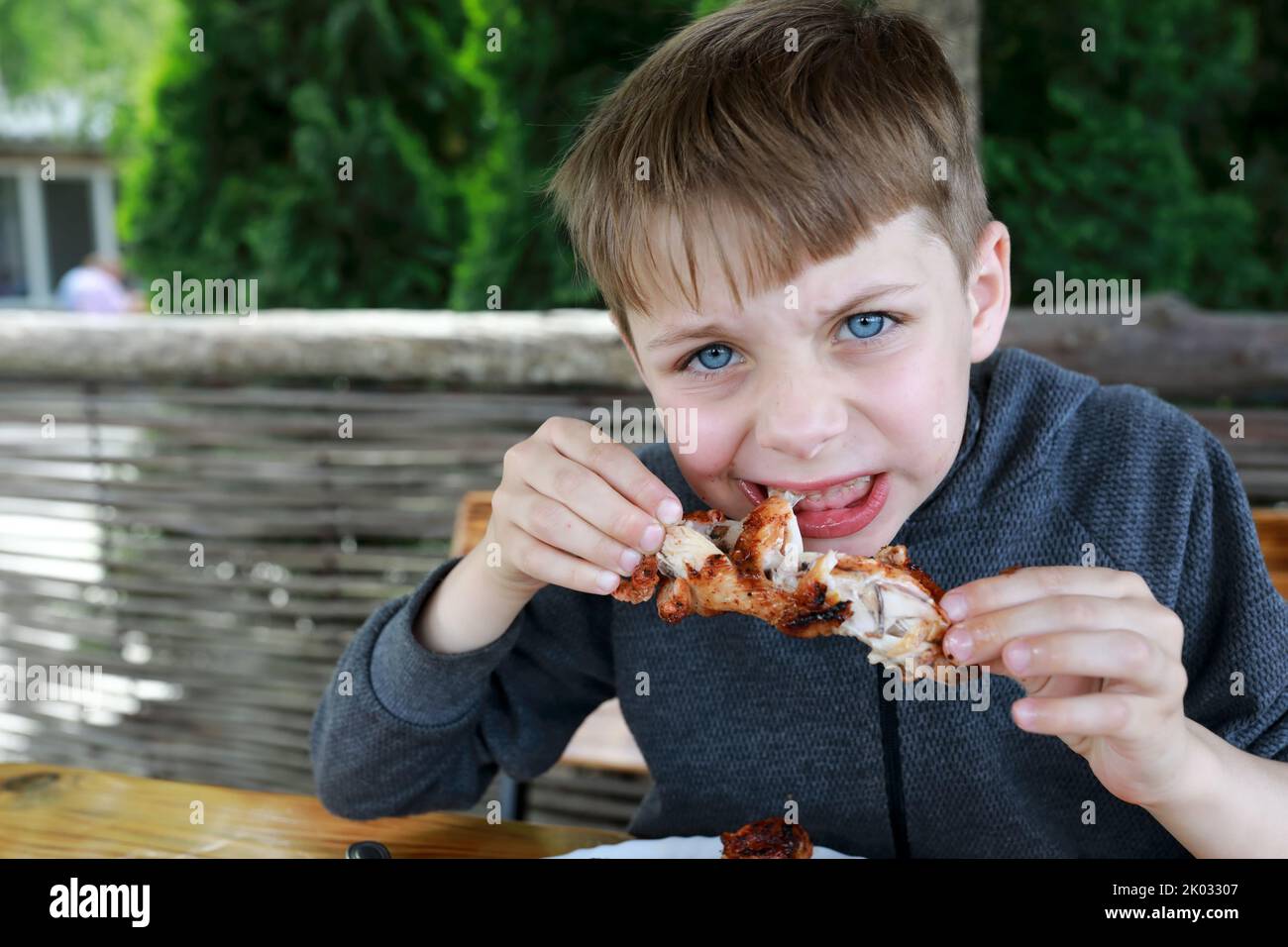 Child has grilled chicken wings on restaurant terrace Stock Photo - Alamy