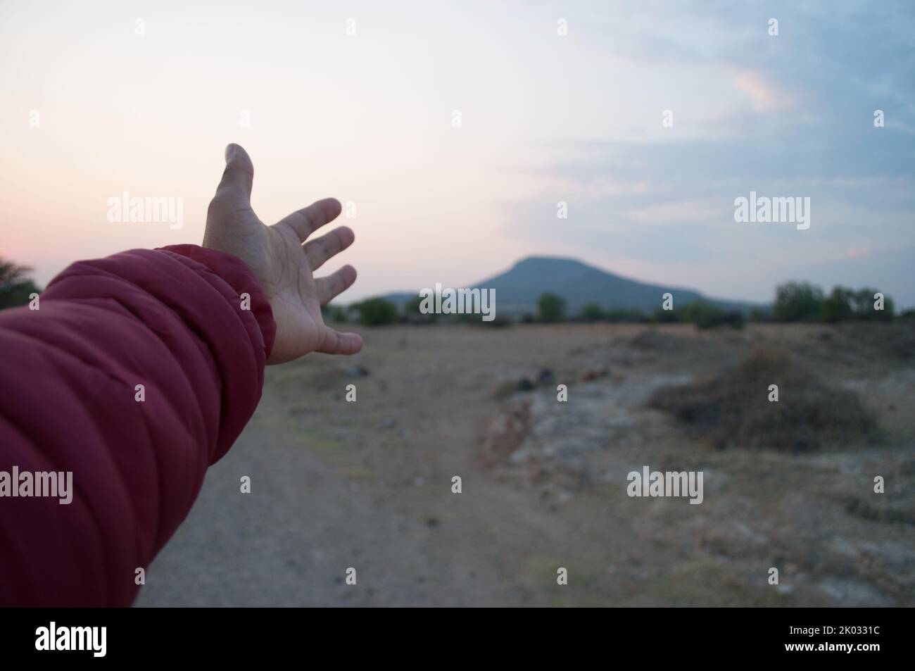 A person's hand pointing at mountains and a plain landscape Stock Photo ...