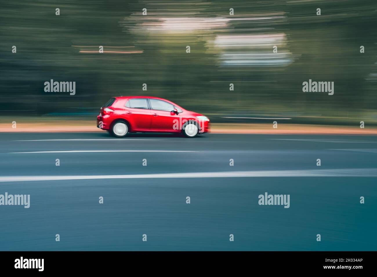A motion blur shot of a red car driving fast in a road Stock Photo - Alamy
