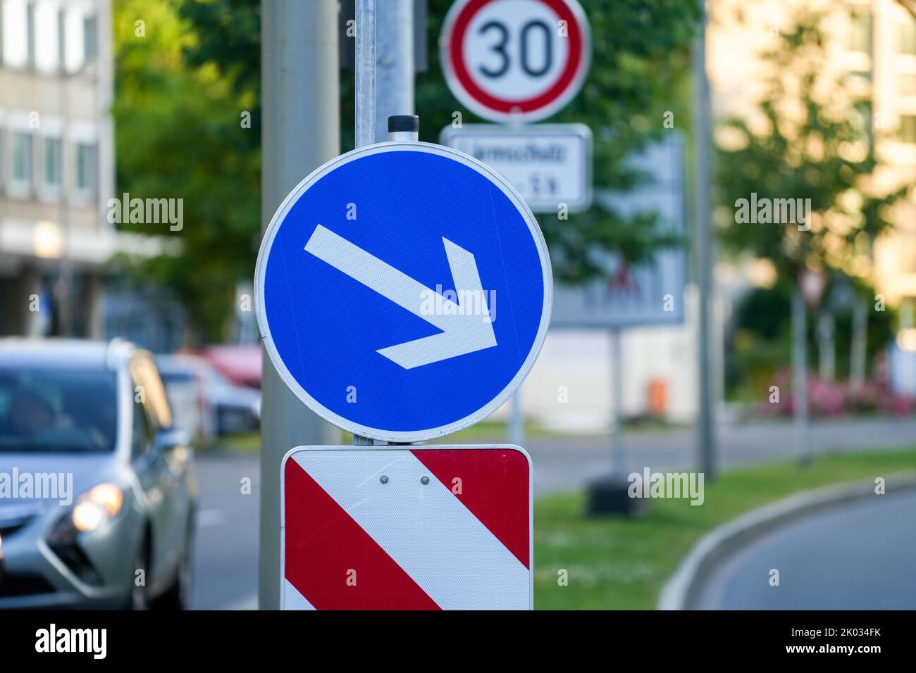 A closeup shot of a blue circular traffic sign with an arrow pointing ...