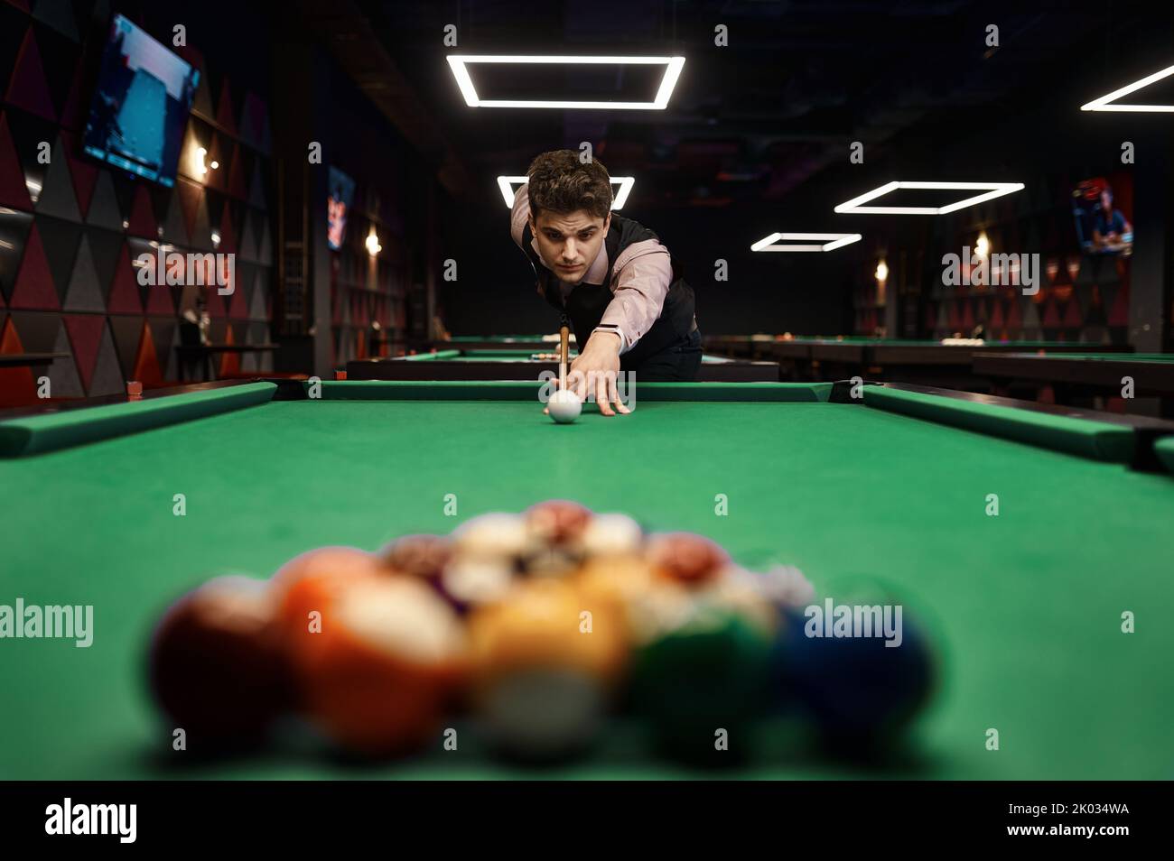 Young man aiming with billiards cue Stock Photo - Alamy