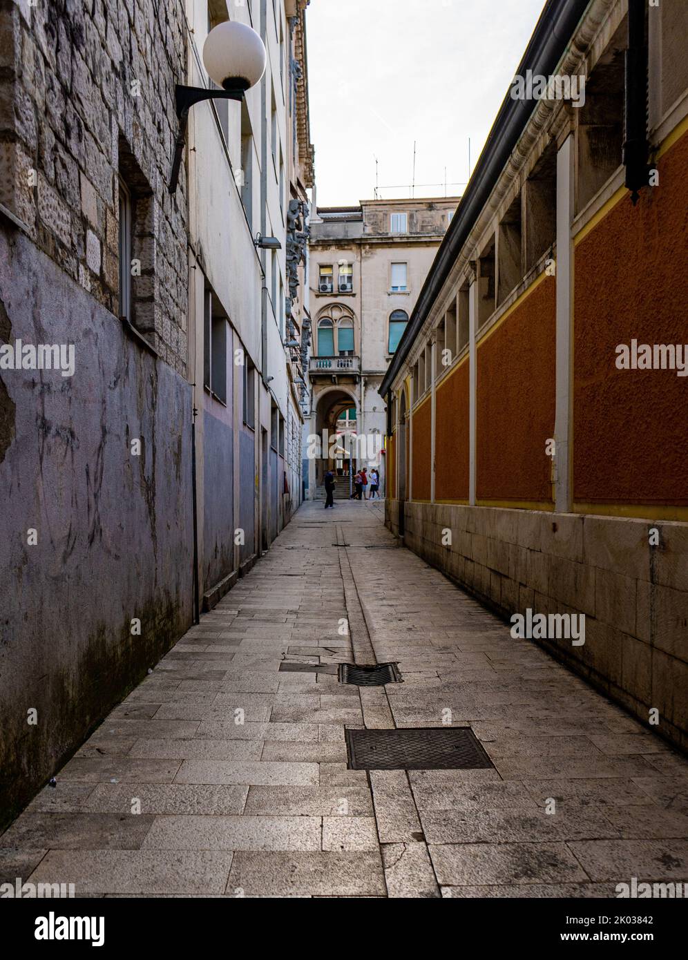 A street in an alley with tall buildings on the side Stock Photo - Alamy