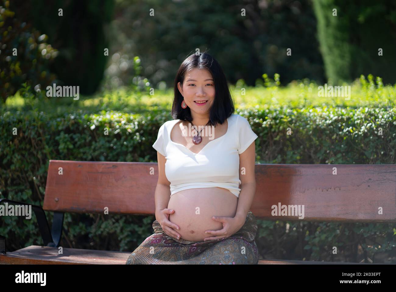 young happy and beautiful Asian Korean woman pregnant showing her belly ...