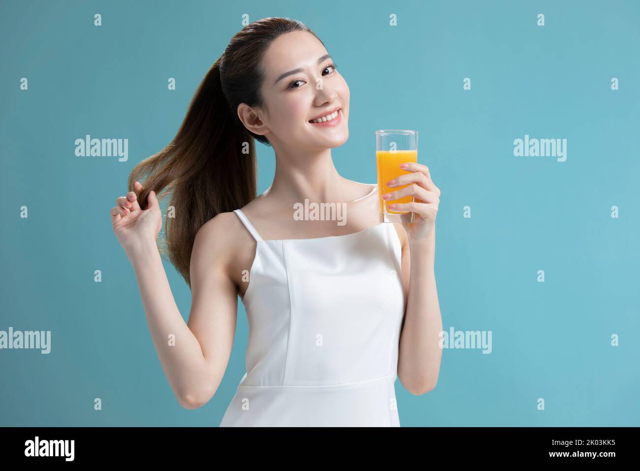 Beautiful young Chinese woman drinking orange juice Stock Photo - Alamy