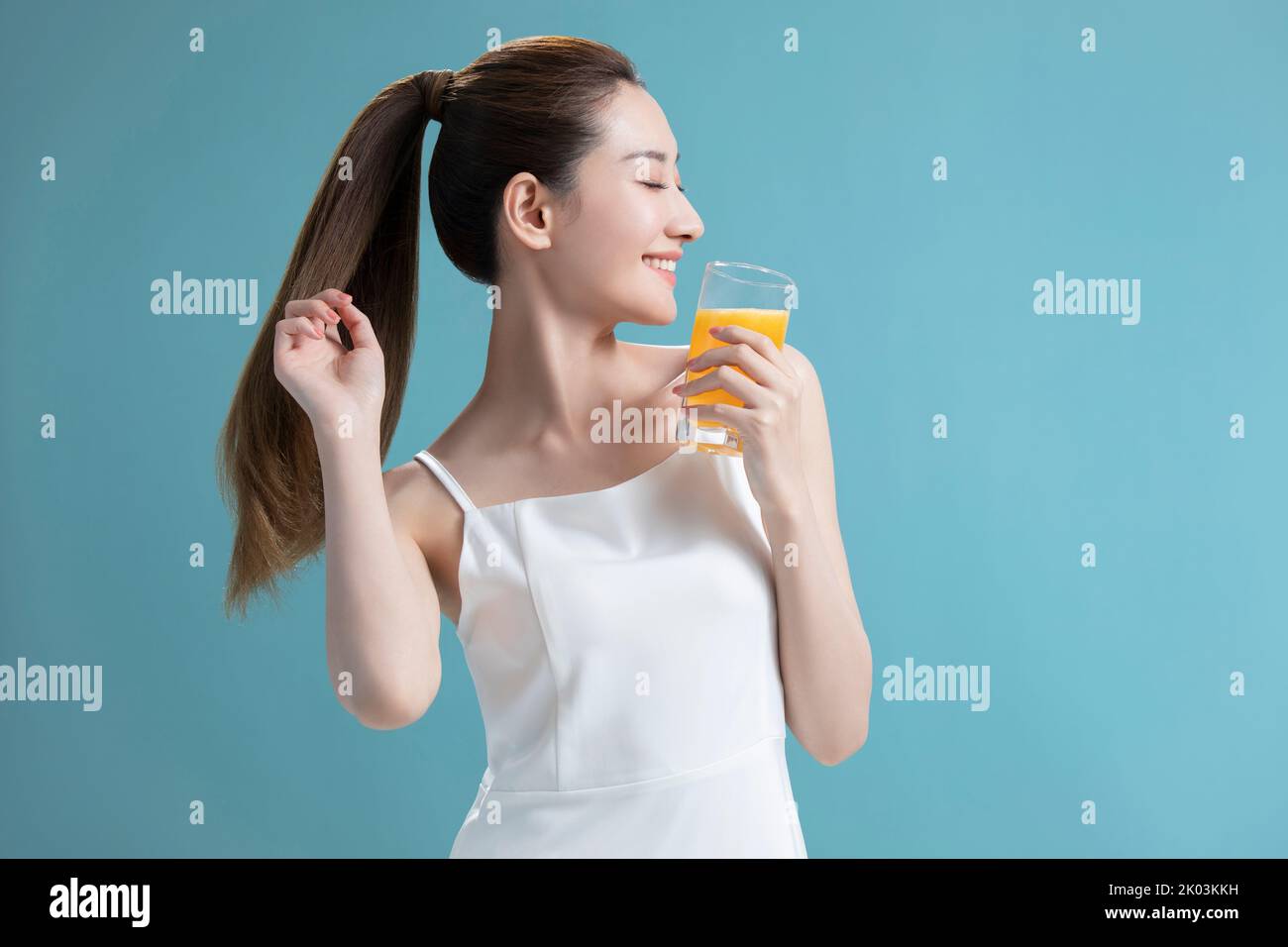 Beautiful young Chinese woman drinking orange juice Stock Photo - Alamy