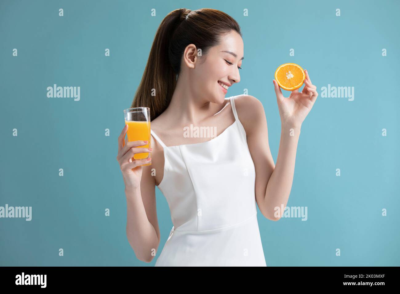 Beautiful young Chinese woman drinking orange juice Stock Photo - Alamy