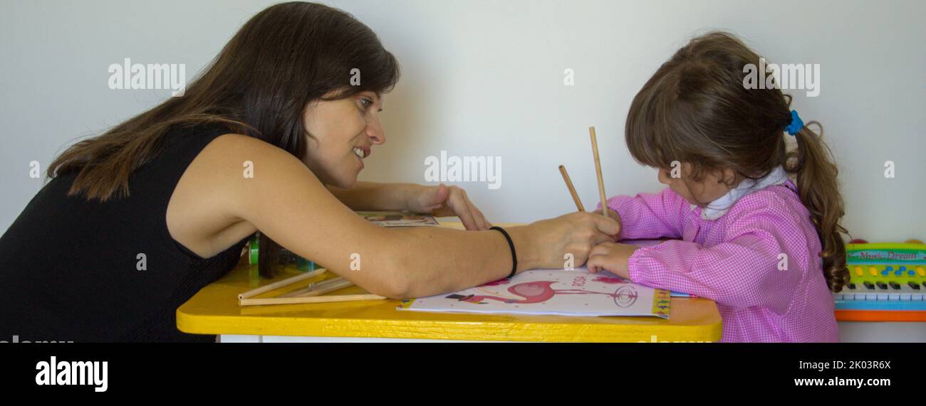 Image Of A Young Mom Teaching Her Daughter To Color With Pencils