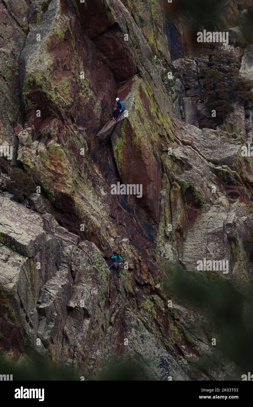 two rock climbers in blue scale up a steep face in Eldorado canyon in ...