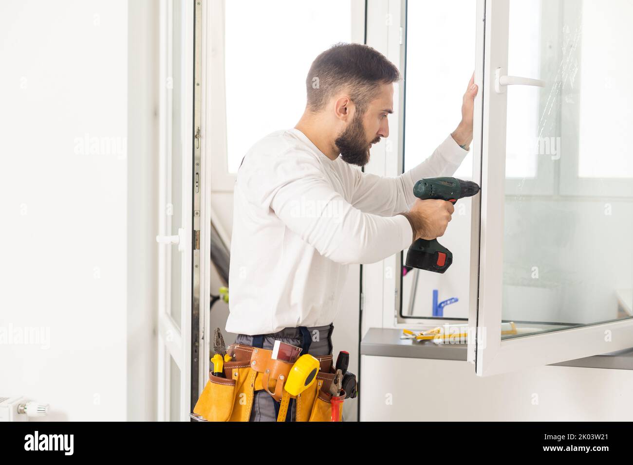 service man installing window with screwdriver Stock Photo - Alamy
