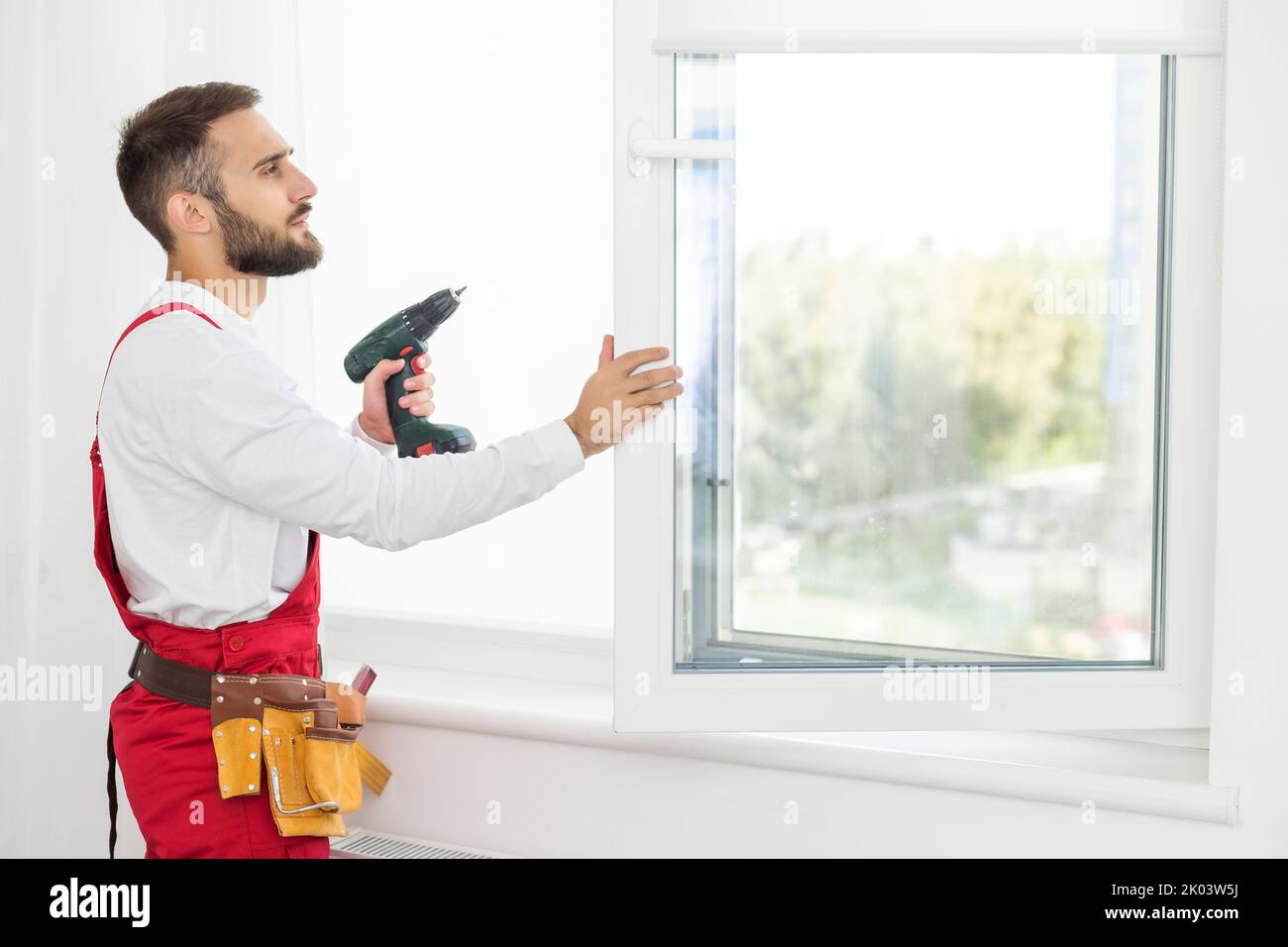handsome young man installing bay window in a new house construction ...