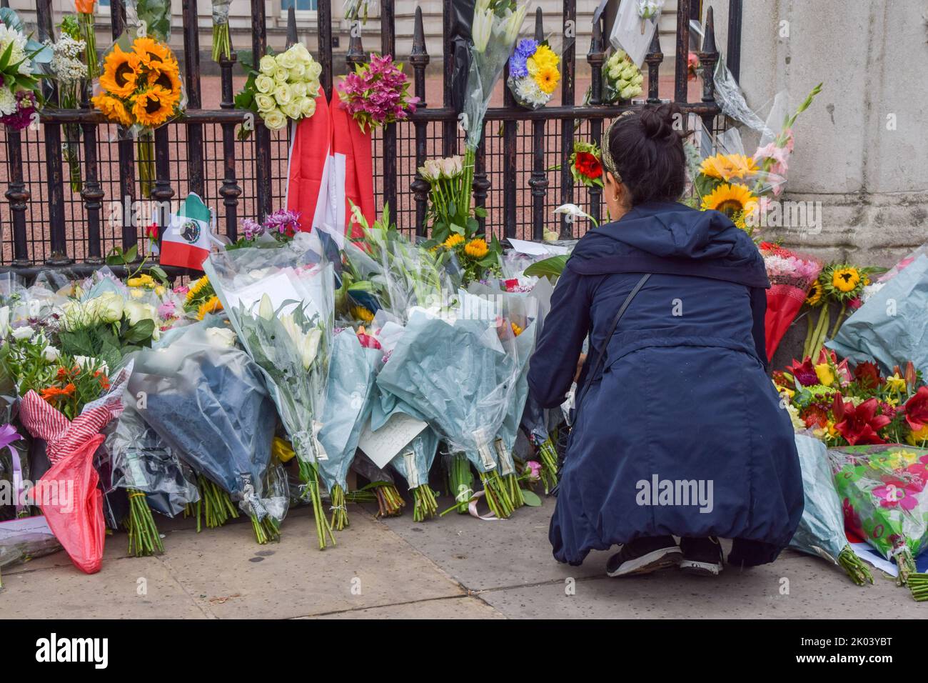 A woman leaves flowers outside Buckingham Palace as Queen Elizabeth II ...