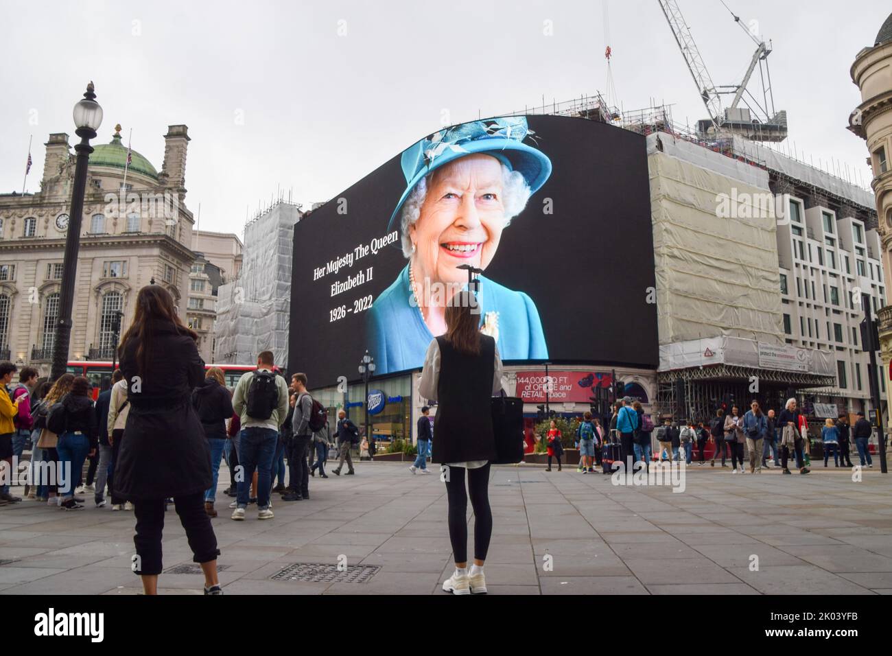 A woman takes a photo of the tribute on Piccadilly Lights in Piccadilly ...