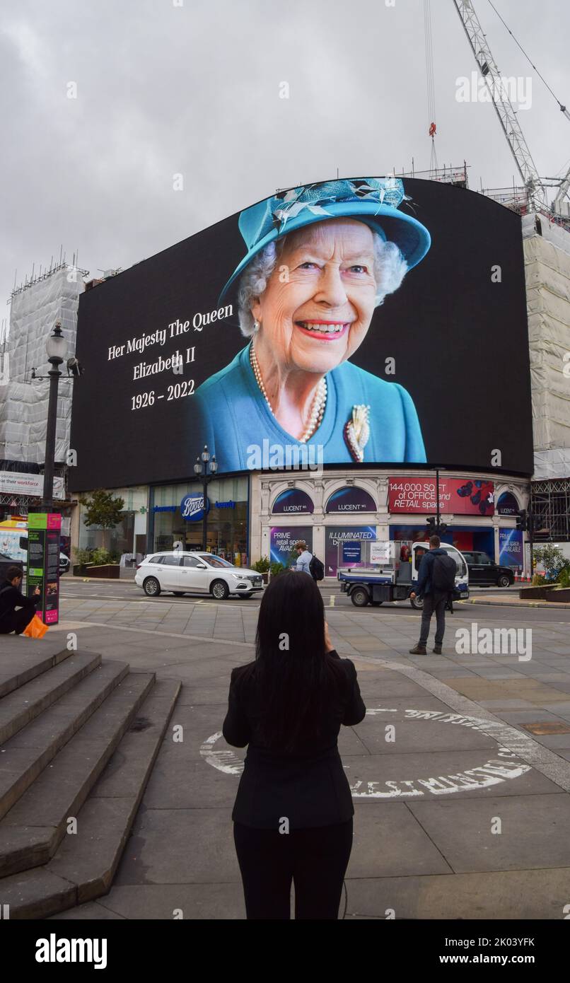 A woman takes a photo of the tribute on Piccadilly Lights in Piccadilly ...