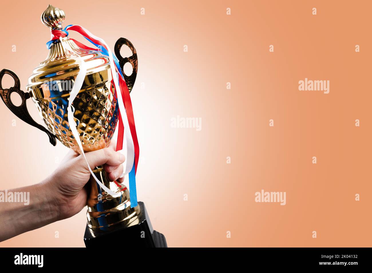 Golden sports cup with medals on multi-colored ribbons in the athlete's ...