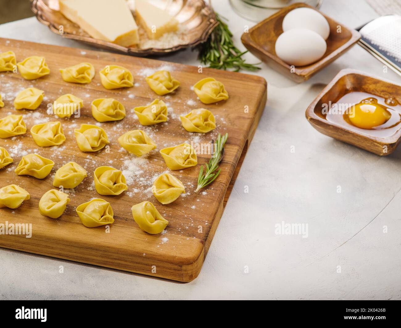 On a white background, raw homemade dumplings on a wooden cutting board ...