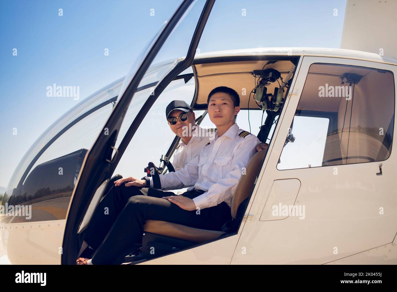 Chinese pilot teaching trainee to operate control panel in cockpit ...