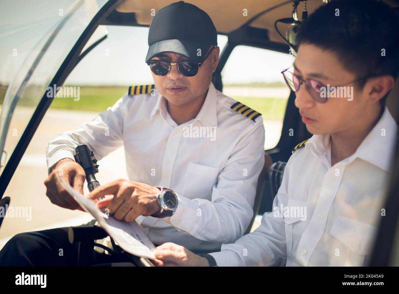 Chinese pilot teaching trainee to operate control panel in cockpit ...