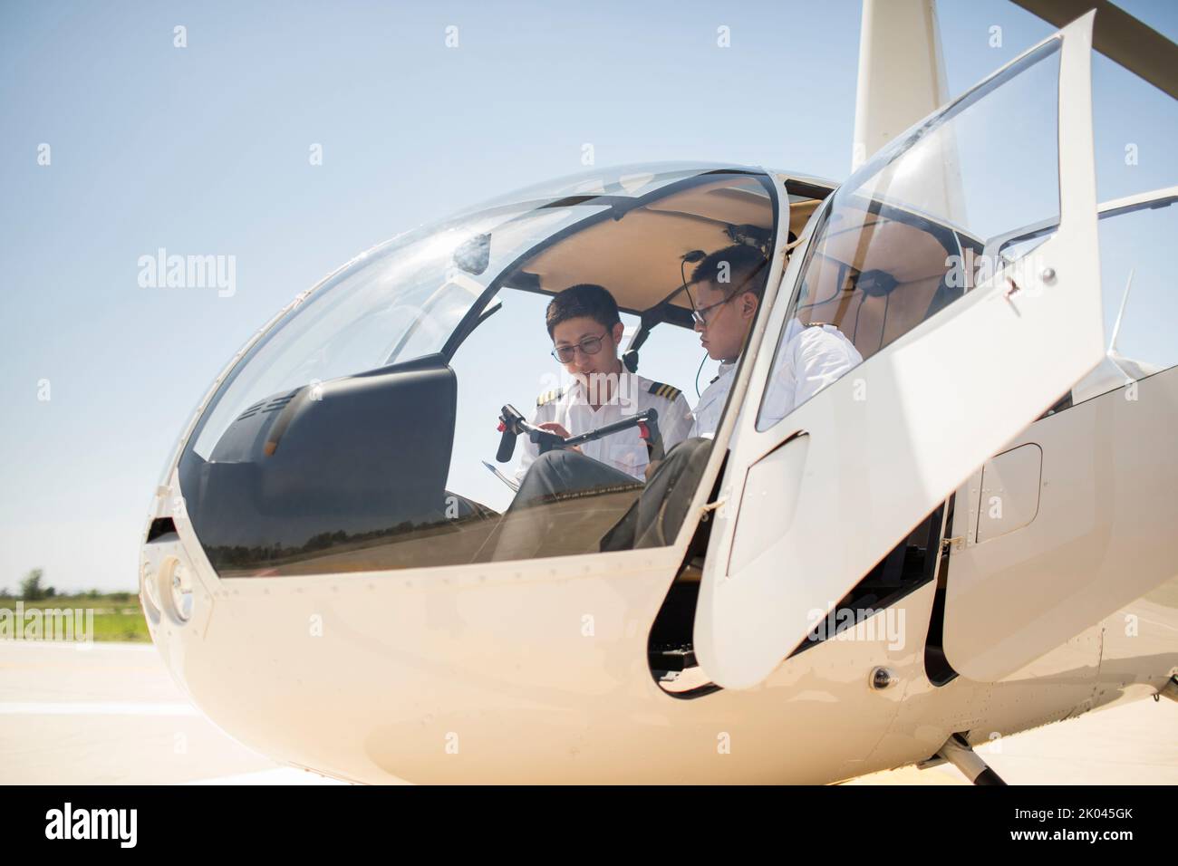 Chinese pilot teaching trainee to operate control panel in cockpit ...