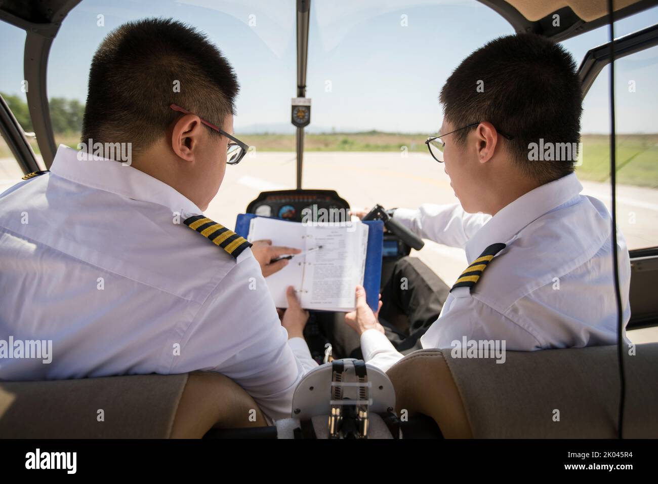Chinese pilot teaching trainee to operate control panel in cockpit ...