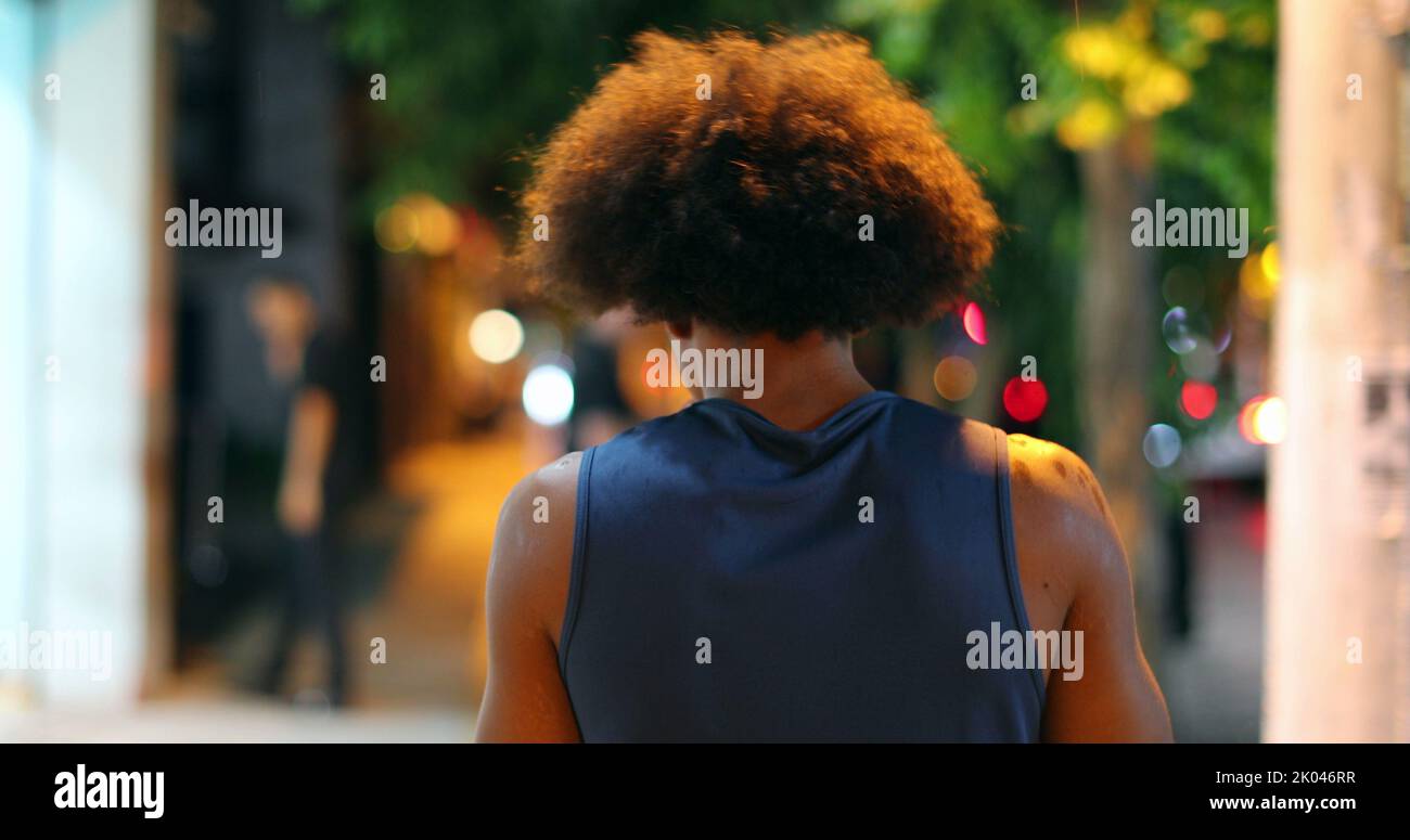 Back of african american black man walking in city sidewalk at night ...