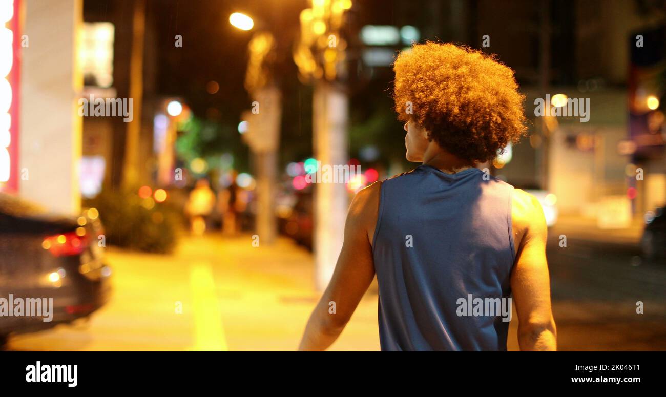 Back Young black african man walking in city at night when raining ...
