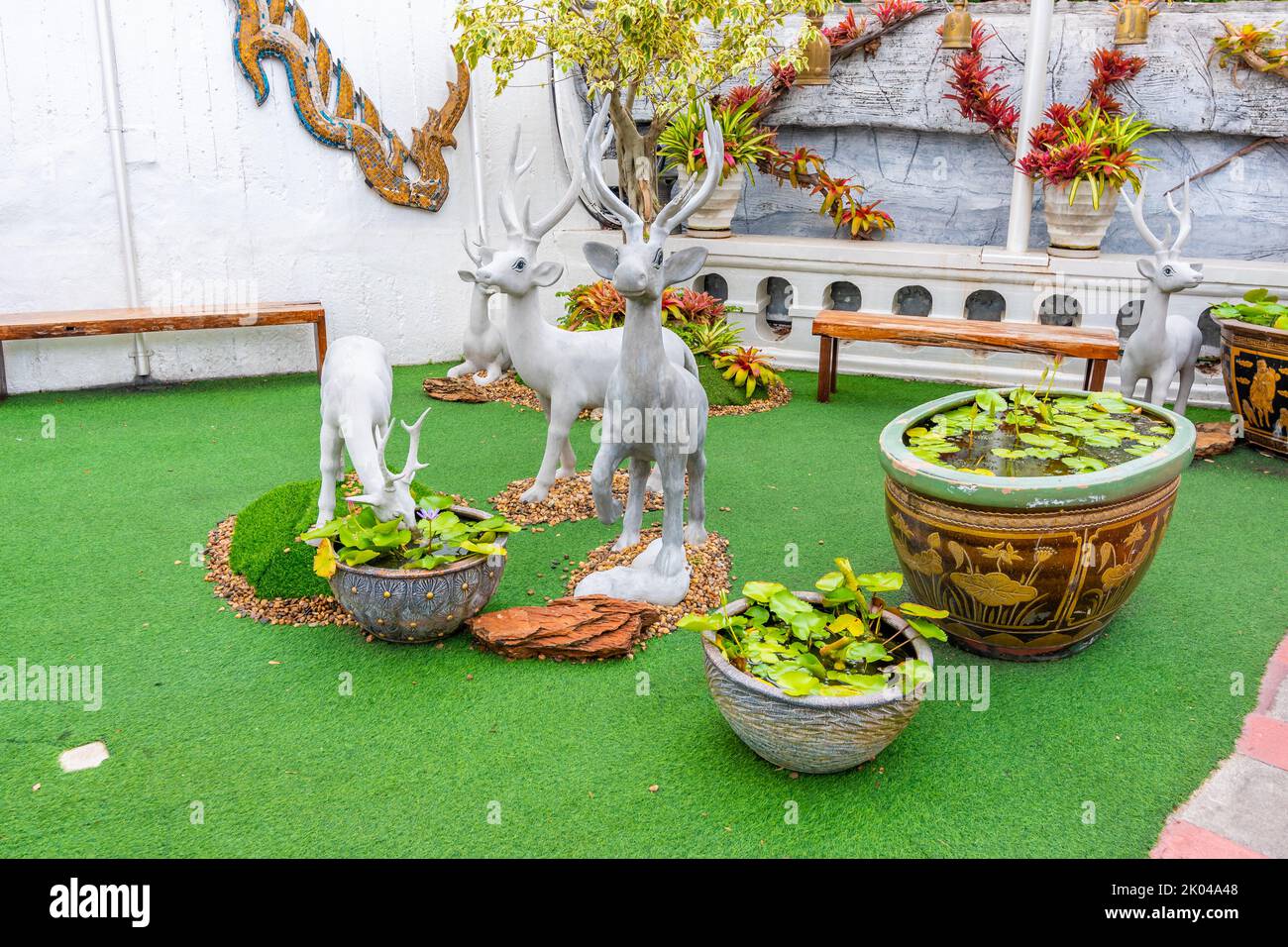 Small deer statues with white color placed on green ground. Waterlily ...