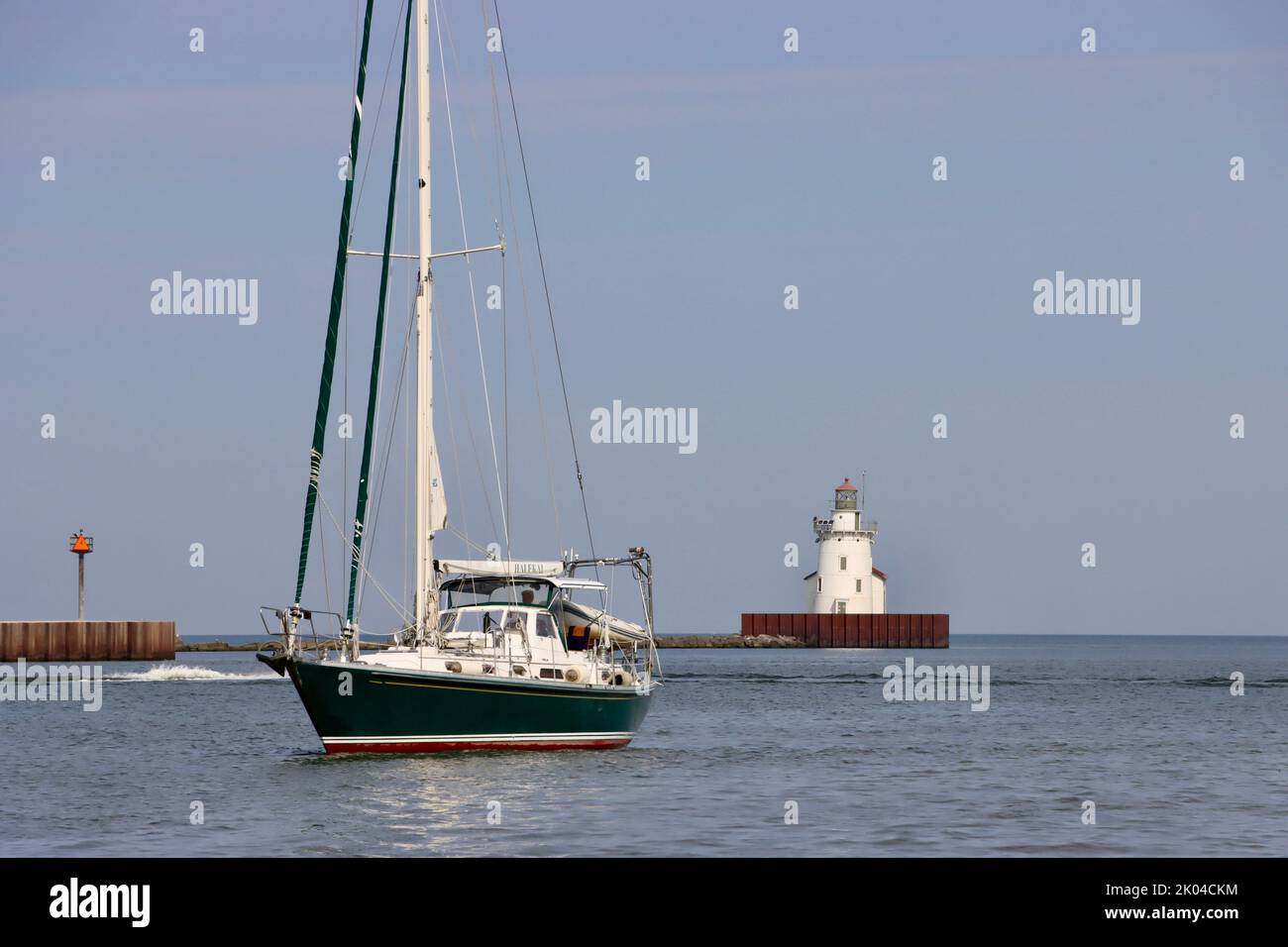A Swan sailboat passing Cleveland harbor West Pierhead Lighthouse Stock ...