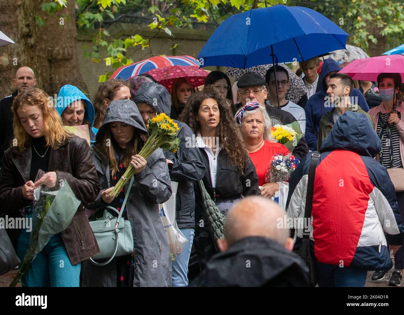 Members of the public queue to lay flowers for the Queen at the gates ...