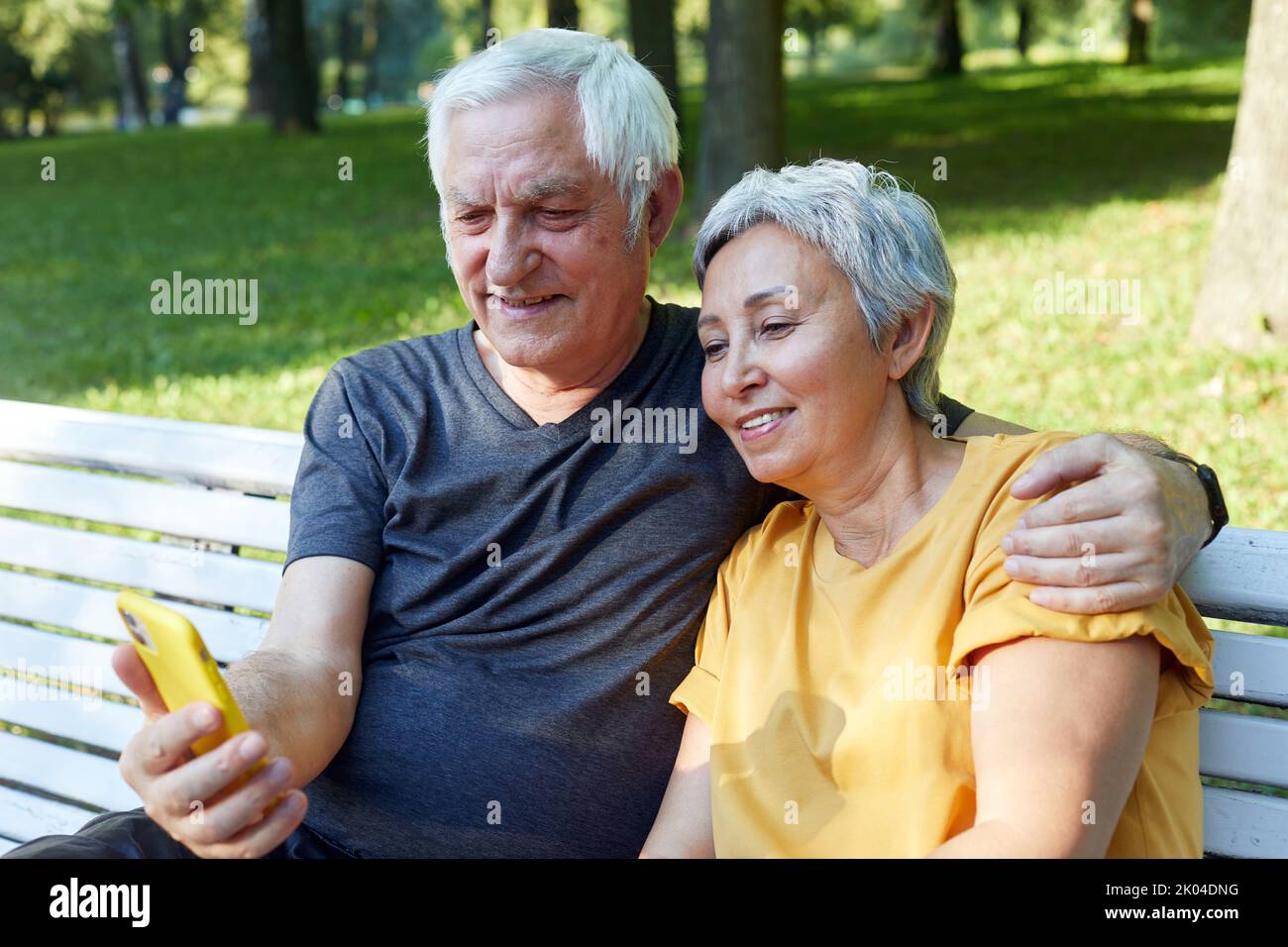 Happy senior spouses take selfie picture sit on bench in summer park ...