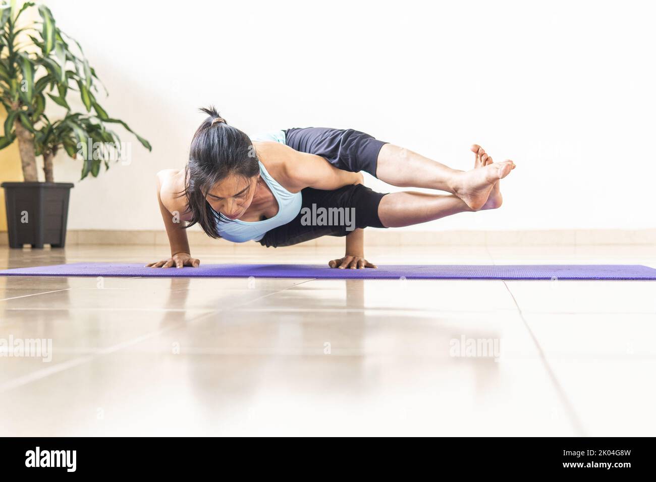 Mature woman practicing yoga, Astavakrasana or eight angle posture on a ...