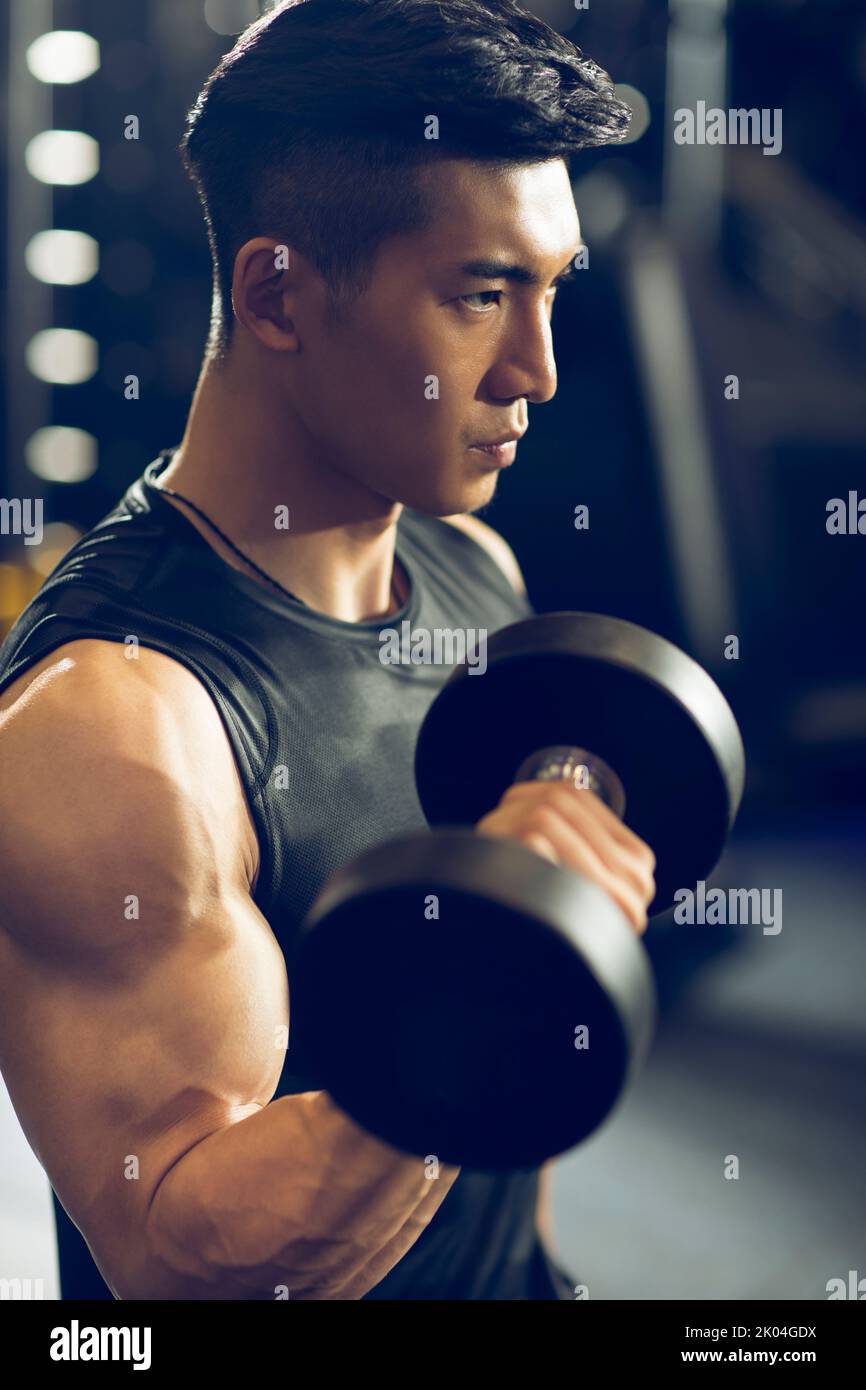 Young Chinese man working out with dumbbell at gym Stock Photo - Alamy