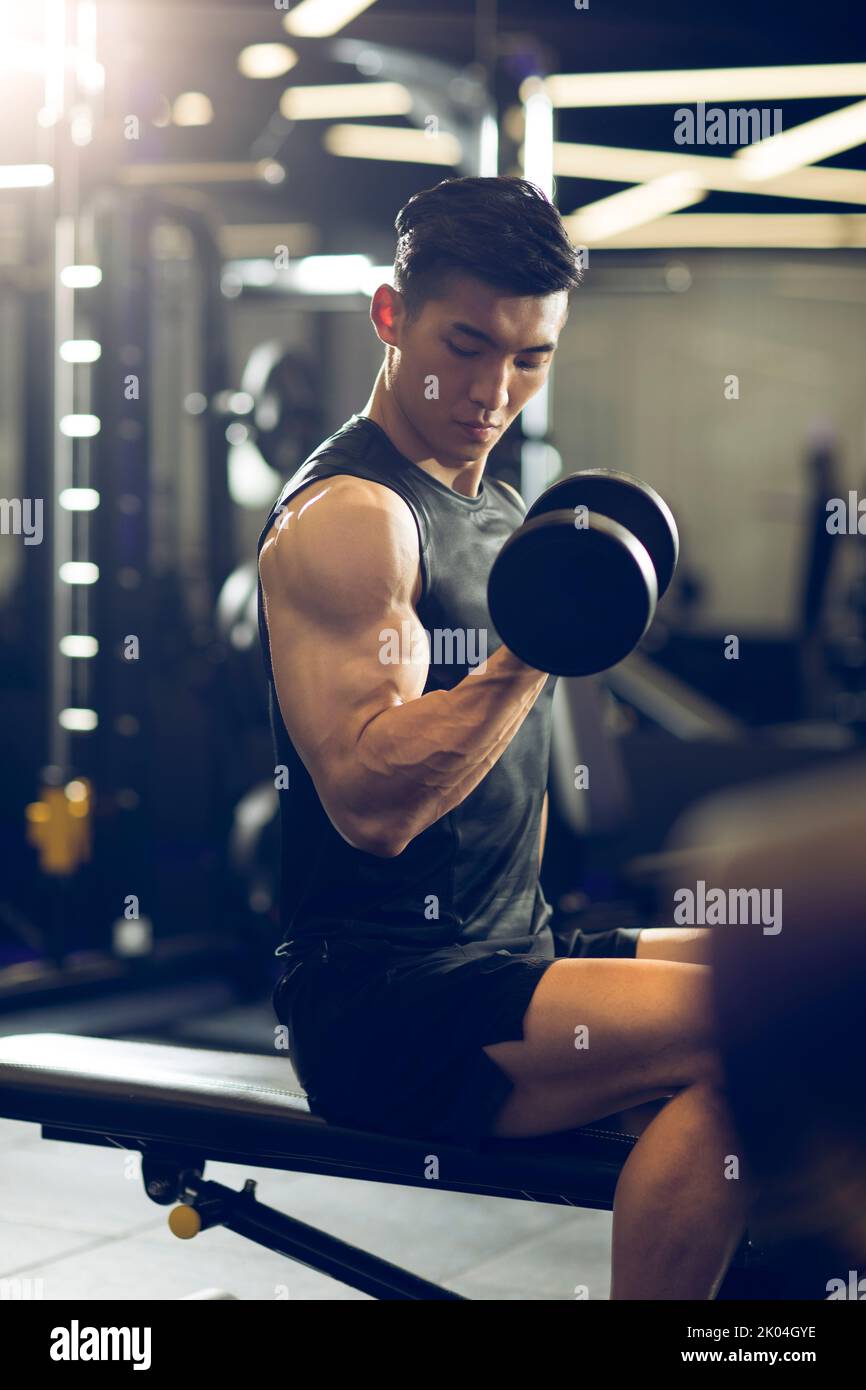 Young Chinese man working out with dumbbell at gym Stock Photo - Alamy